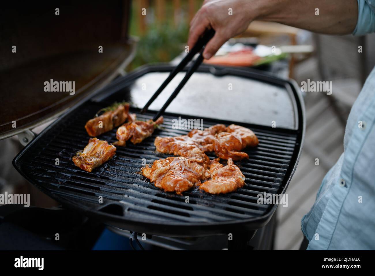 Unrecognizable man grilling meat, ribs and wings, on grill during ...