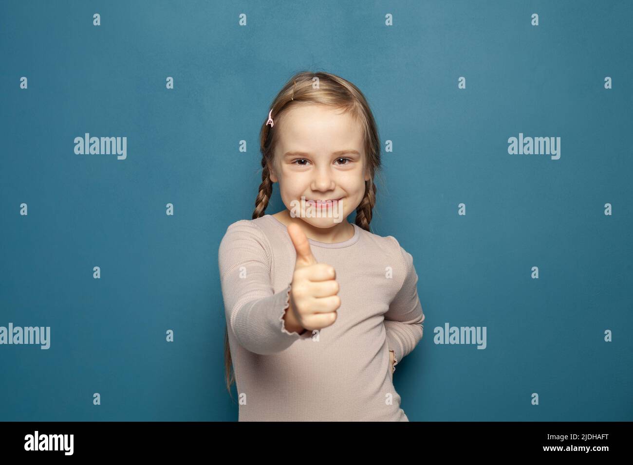 Cute happy smiling kid girl showing thumb up on blue background Stock ...