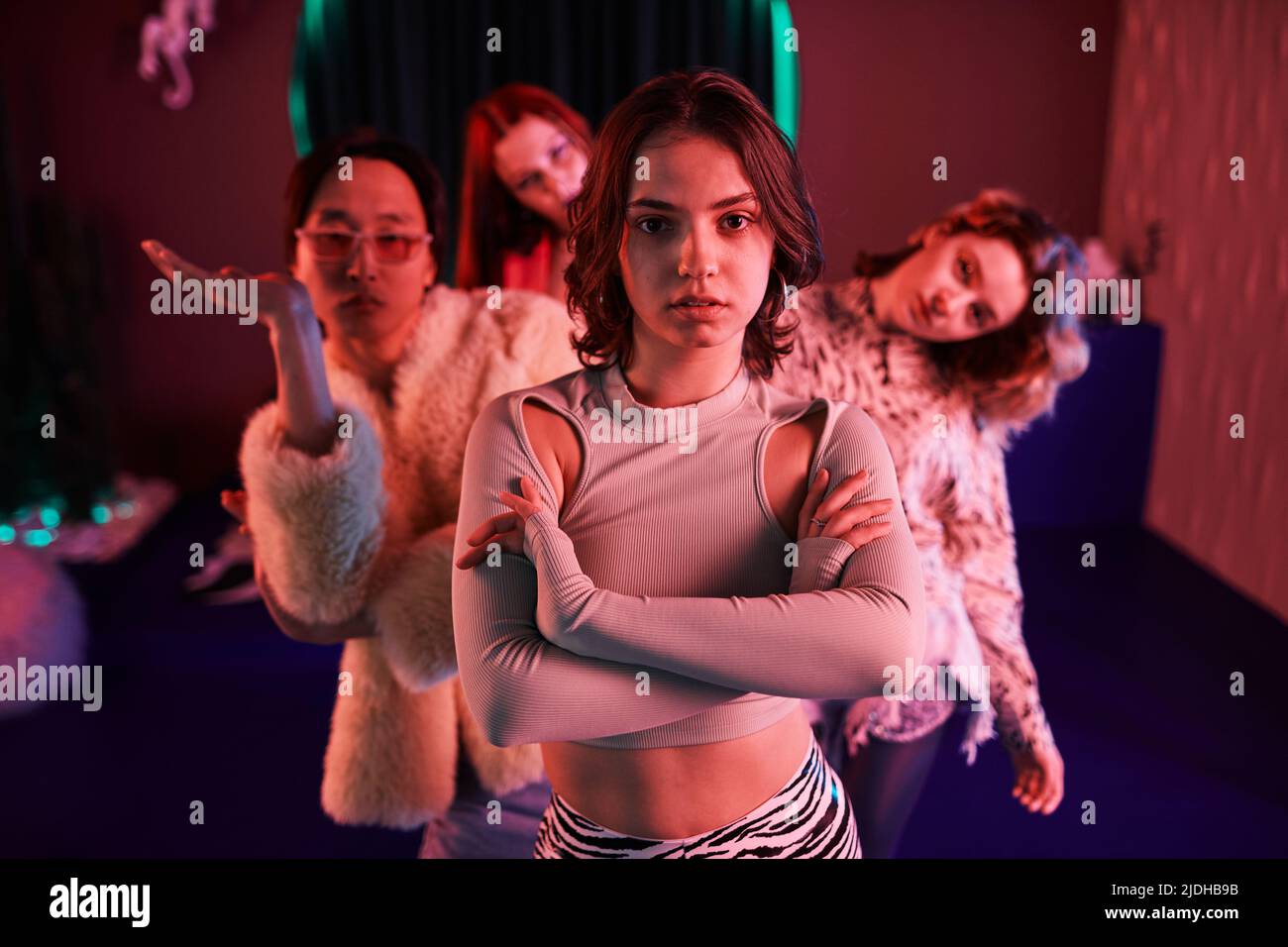 Waist up portrait of vogue dance crew posing in pink neon light, focus ...
