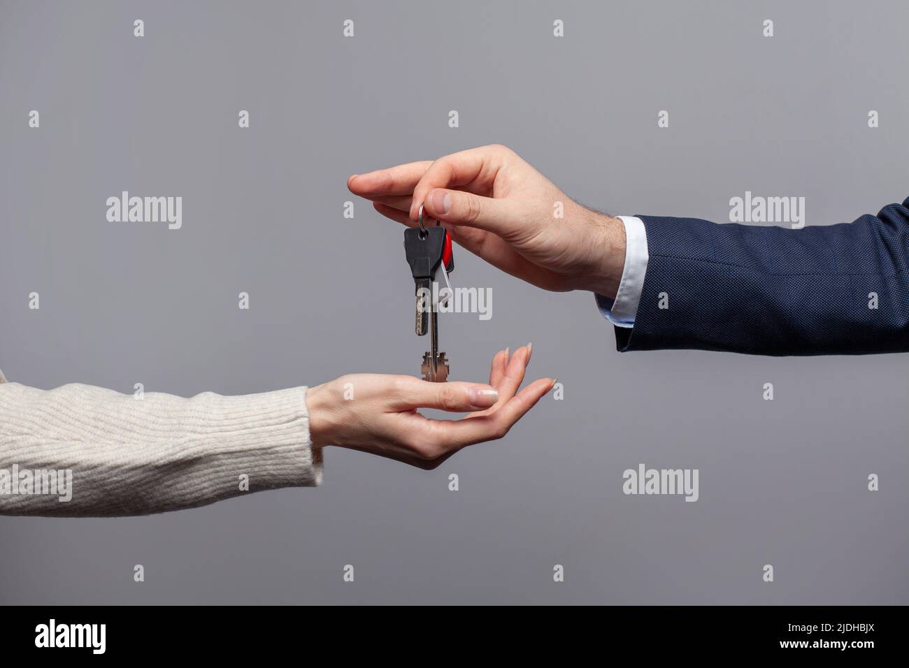 Male hand passing house keys to new owner on grey background Stock ...