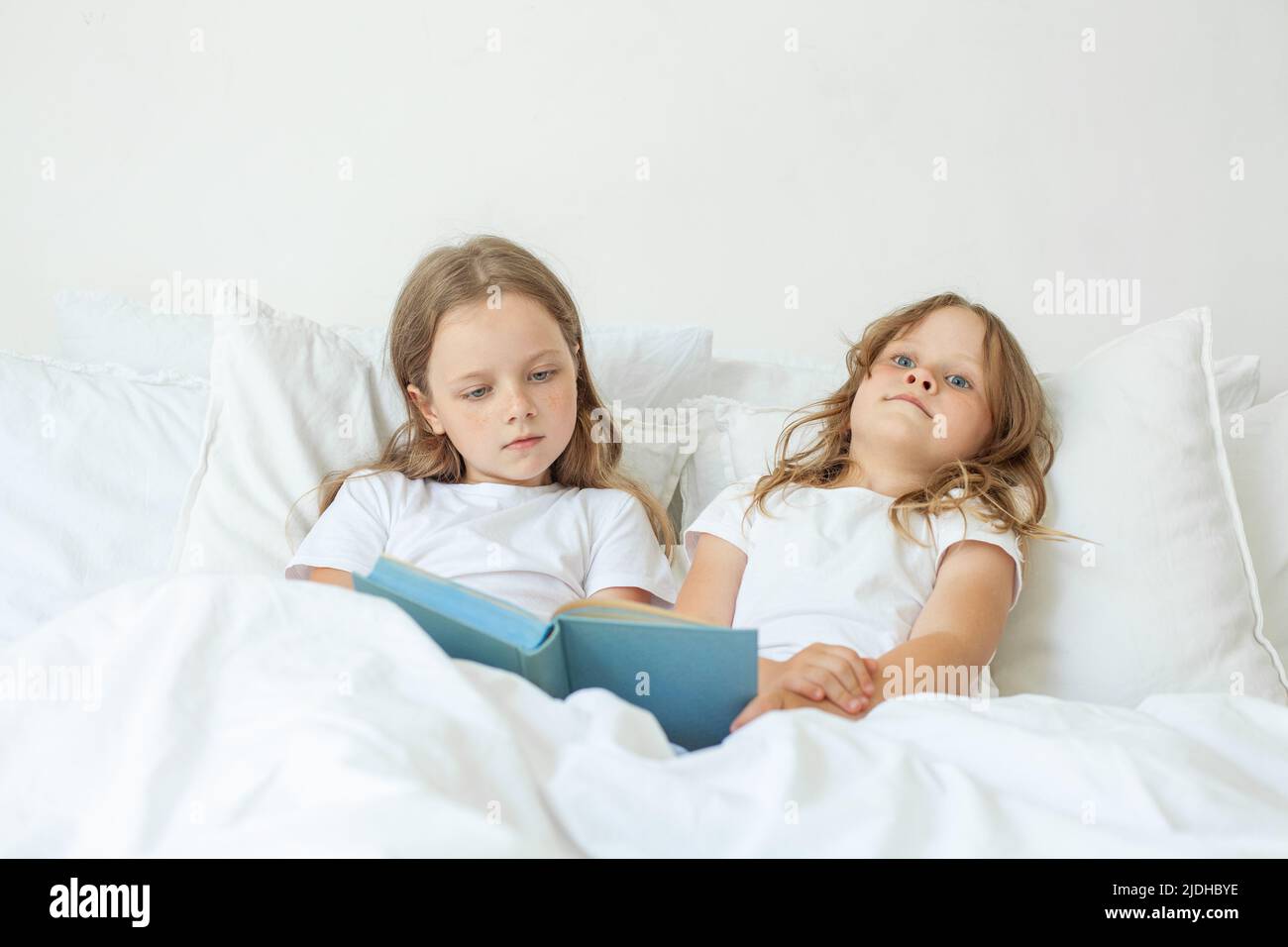 Cute little girls reading a story at home Stock Photo - Alamy