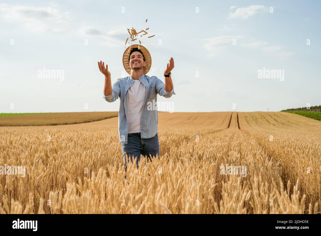 Happy farmer throwing crops in his growing wheat field after successful ...