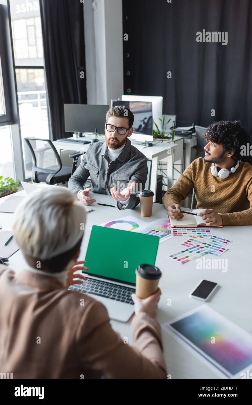 man in eyeglasses talking to multicultural advertising designers in ...