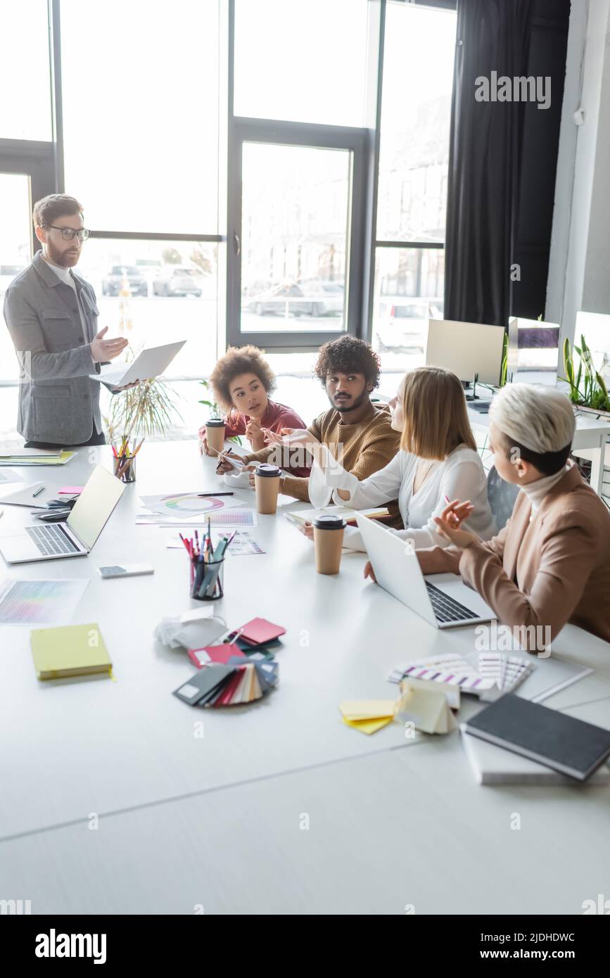 multiethnic advertising managers talking during meeting in office Stock ...
