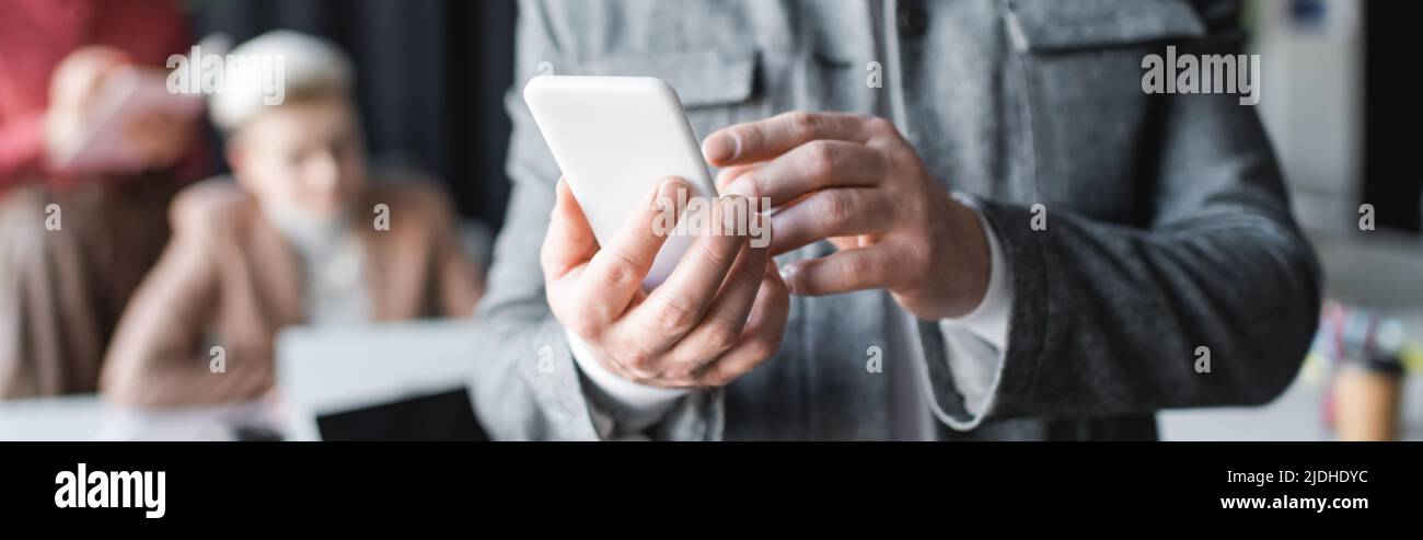 partial view of man using mobile phone in ad agency on blurred ...