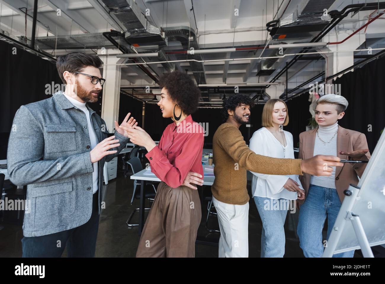indian man pointing at flip chart during discussion with multicultural ...