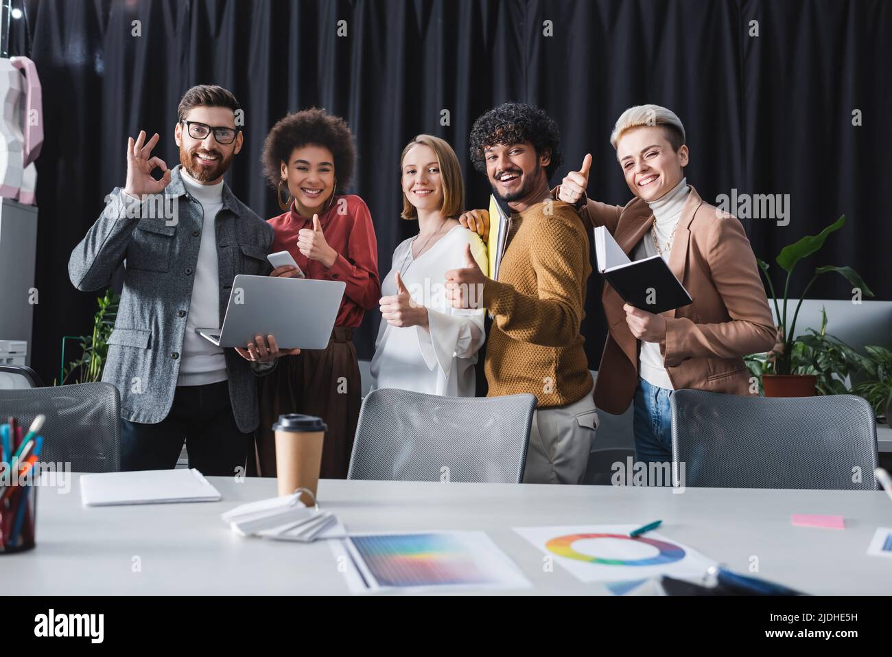 multiethnic advertising agents smiling at camera while showing thumbs ...