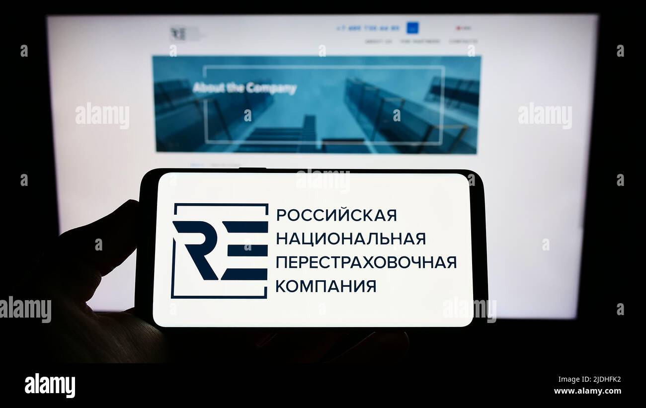 Person holding smartphone with logo of Russian National Reinsurance ...