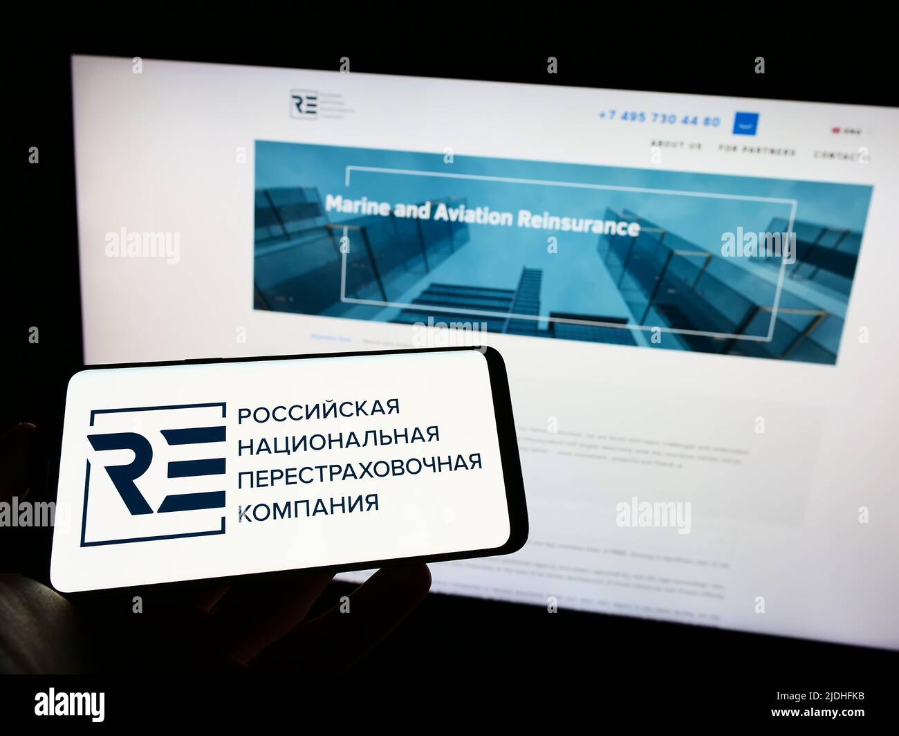 Person holding cellphone with logo of Russian National Reinsurance ...