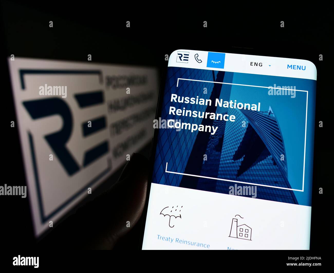 Person holding cellphone with webpage of Russian National Reinsurance ...