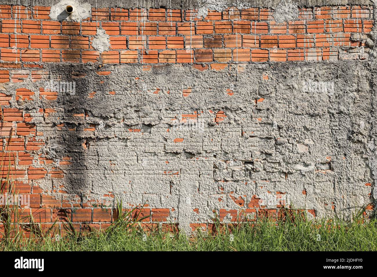 Wall mute with plaster and some exposed bricks, with signs of time, highlighting its texture and ...