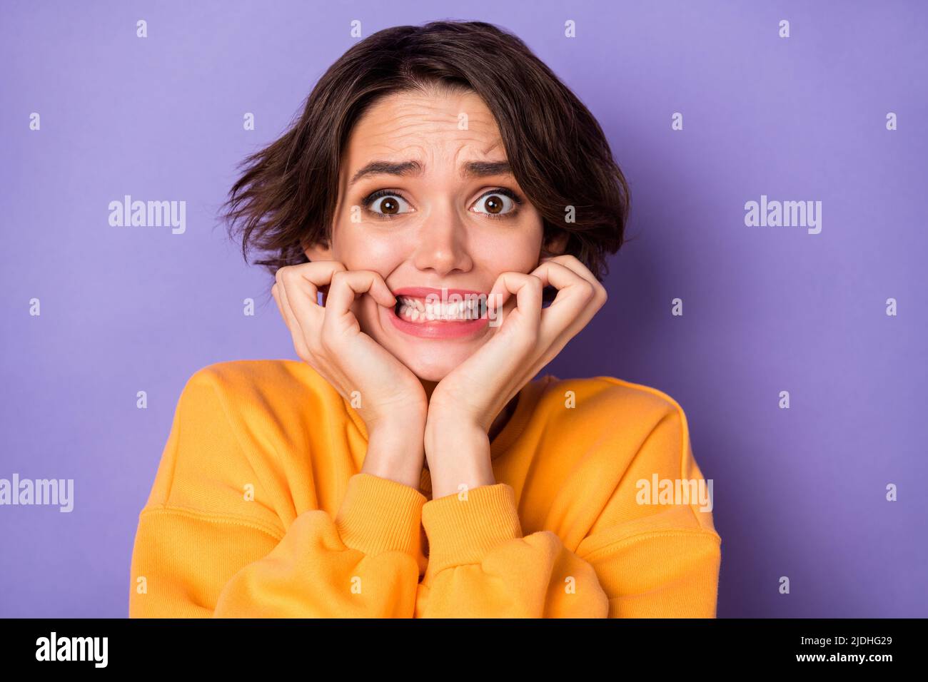 Photo of scared young person arms touch cheeks biting finger nails ...