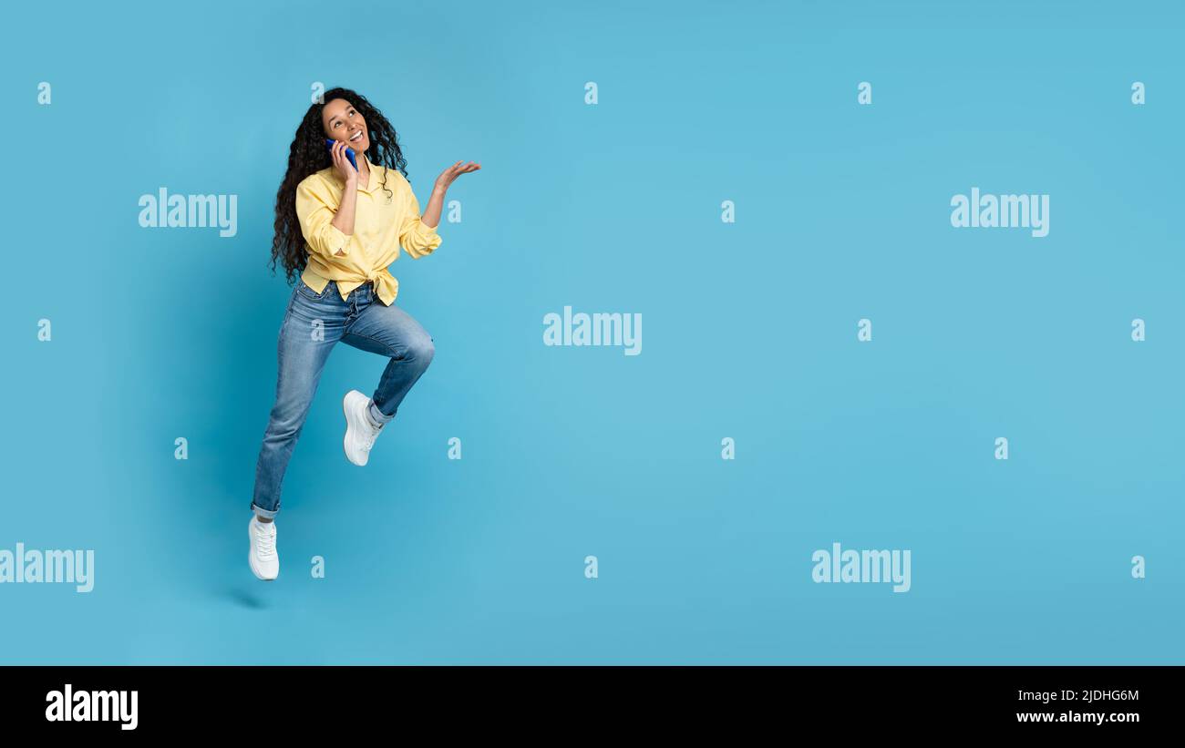 Full length of excited millennial woman jumping and running with mobile ...