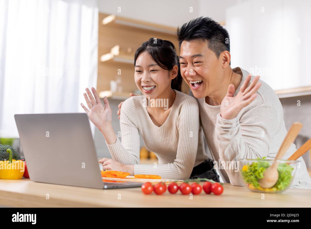 Happy asian spouses having video call while cooking at kitchen Stock ...