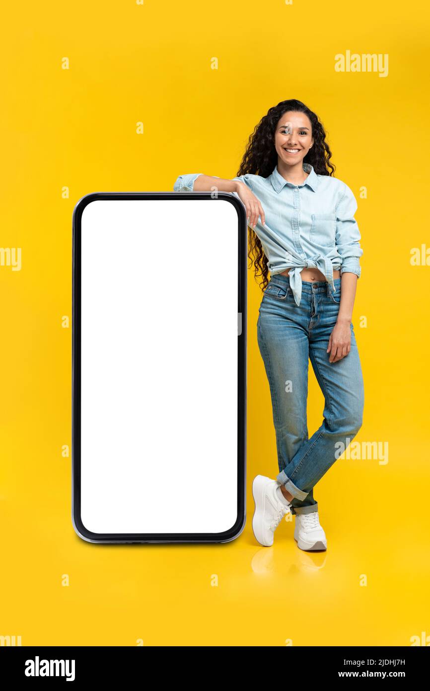 Young lady standing near big smartphone with empty screen ...