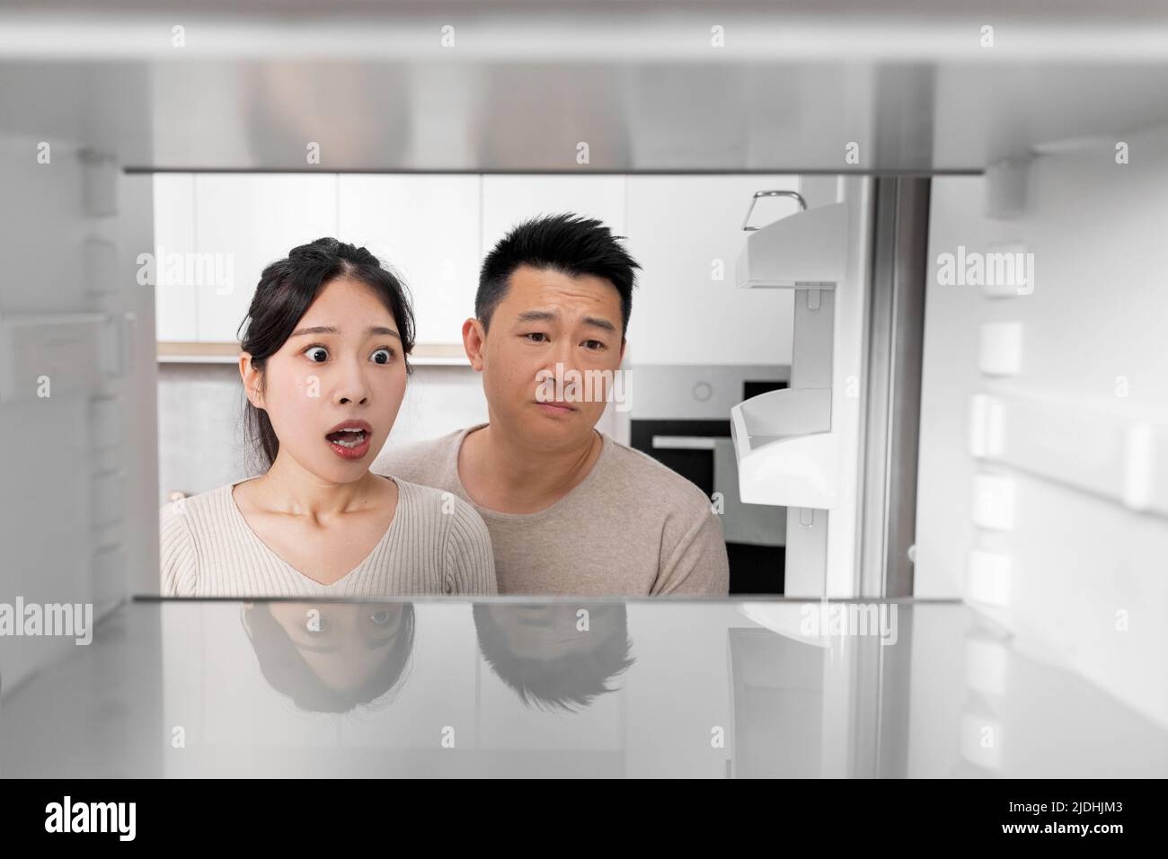 Shocked asian couple looking inside empty fridge at home Stock Photo ...
