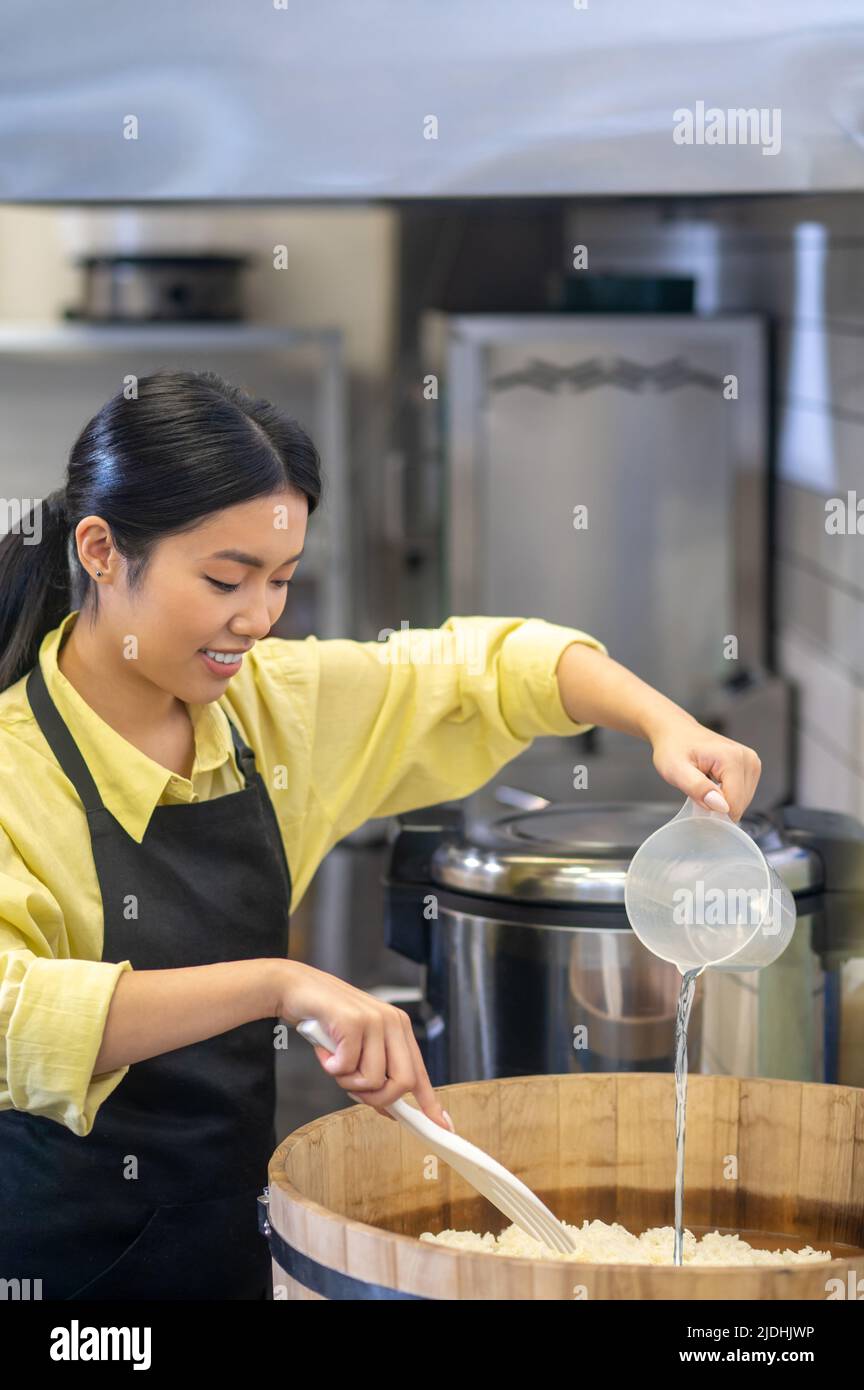 Woman pouring water from jug into bowl of food Stock Photo - Alamy