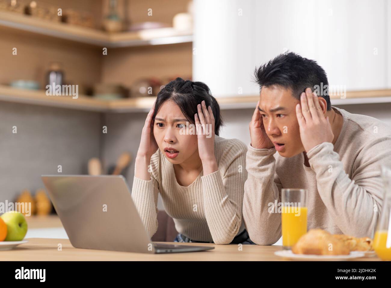 Shocked asian couple looking at laptop screen Stock Photo - Alamy