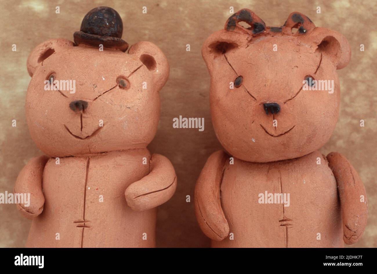 Two small clay model teddy bears standing side by side with one wearing ...
