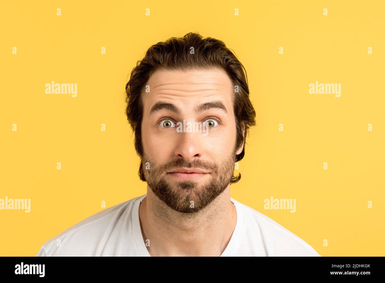 Funny surprised millennial caucasian man with stubble in white t-shirt ...