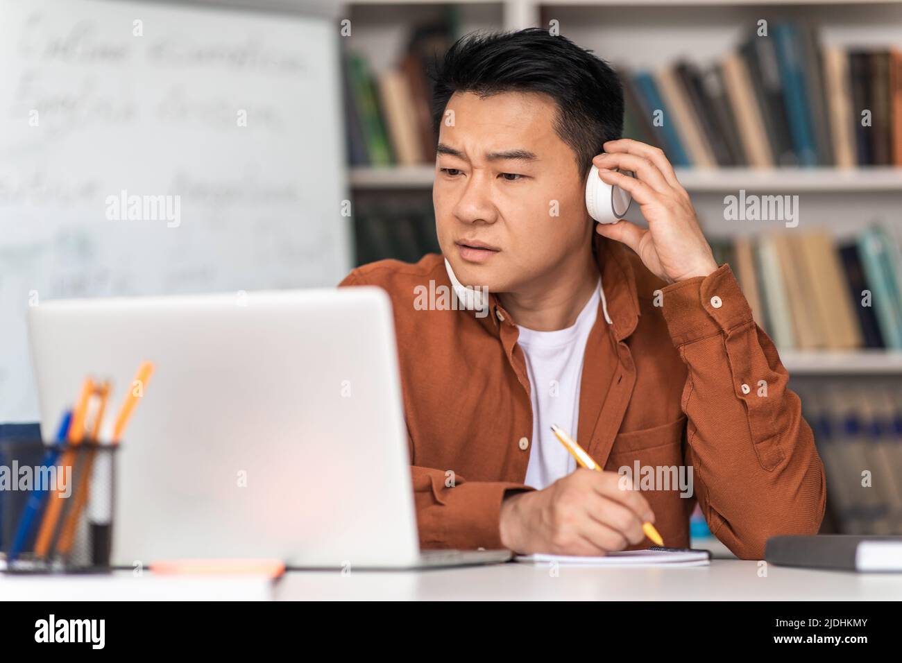 Asian Teacher Man Using Laptop Wearing Headphones In Classroom Indoor ...