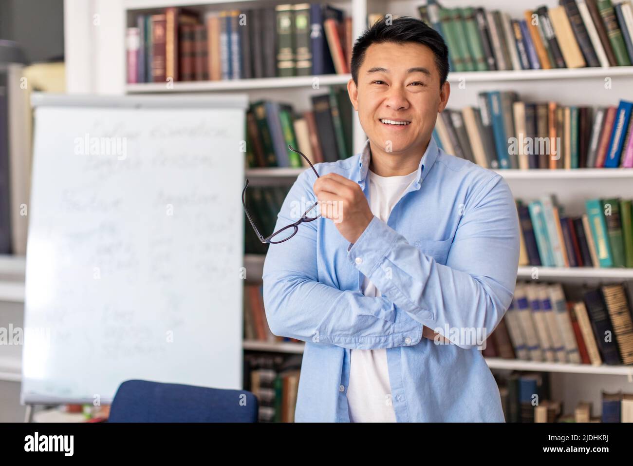 Happy Asian Male Teacher Posing Holding Eyewear Standing In Classroom ...
