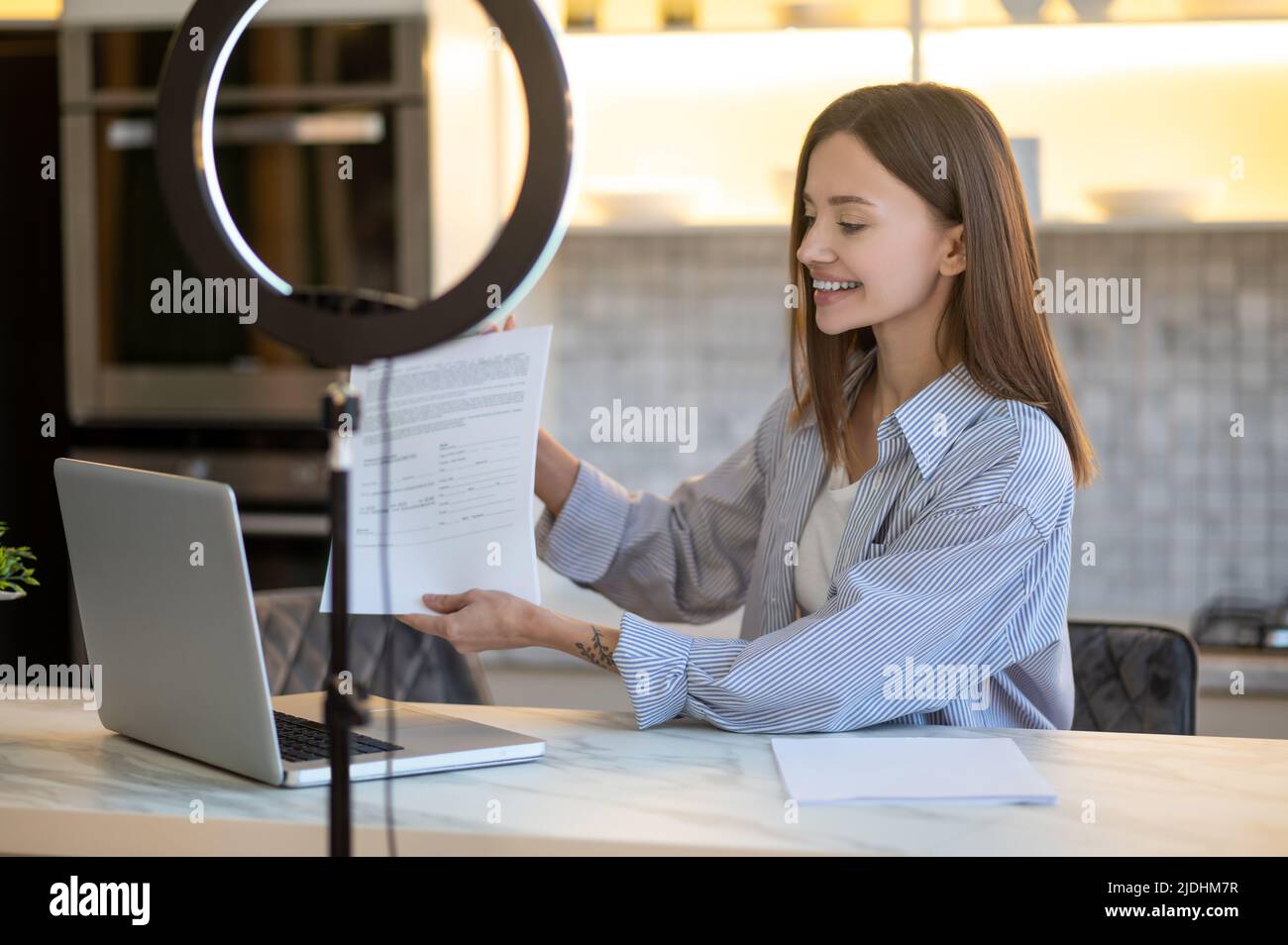 Woman showing document smiling at laptop Stock Photo - Alamy