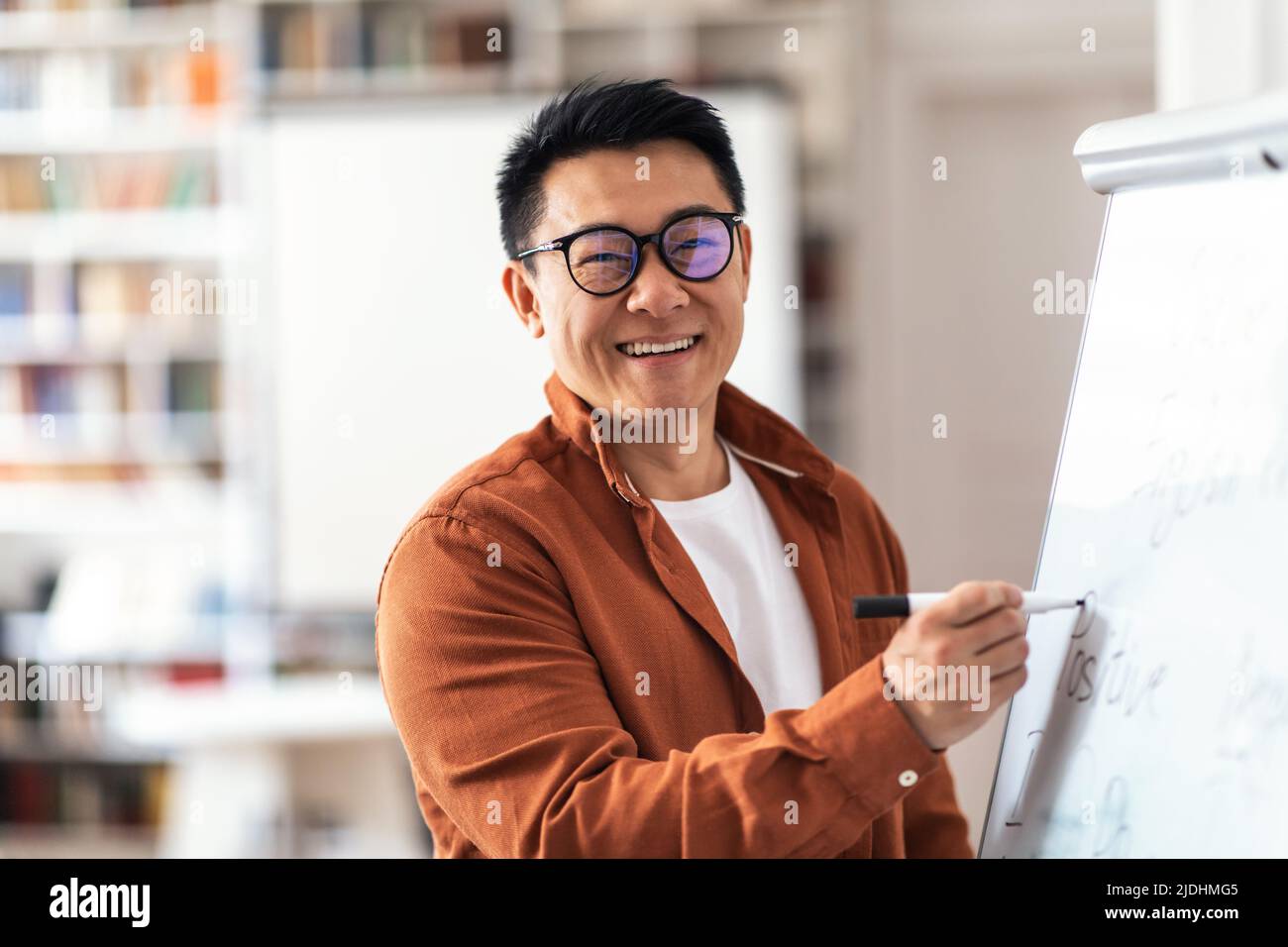 Positive Asian Teacher Man Smiling Writing On Whiteboard In Classroom ...