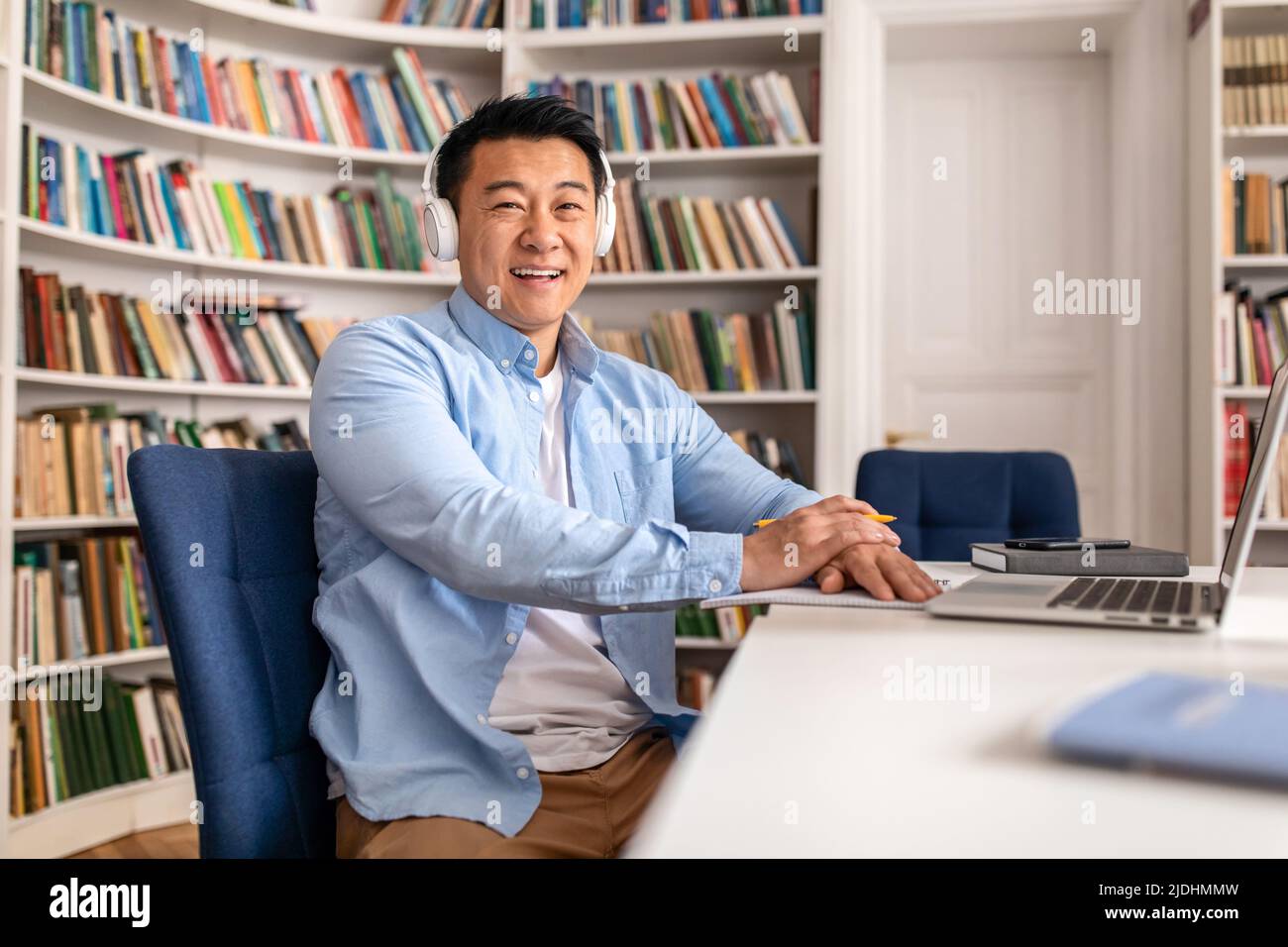 Happy Korean Male Teacher Near Laptop Posing Sitting In Library Stock ...