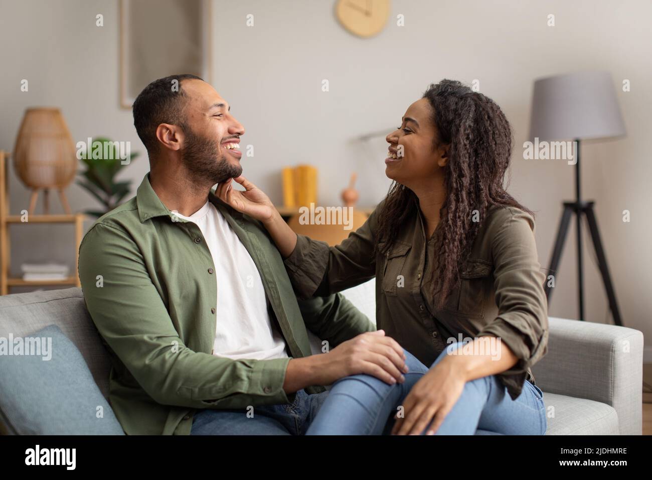 Happy Black Couple Sitting And Hugging At Home Stock Photo - Alamy