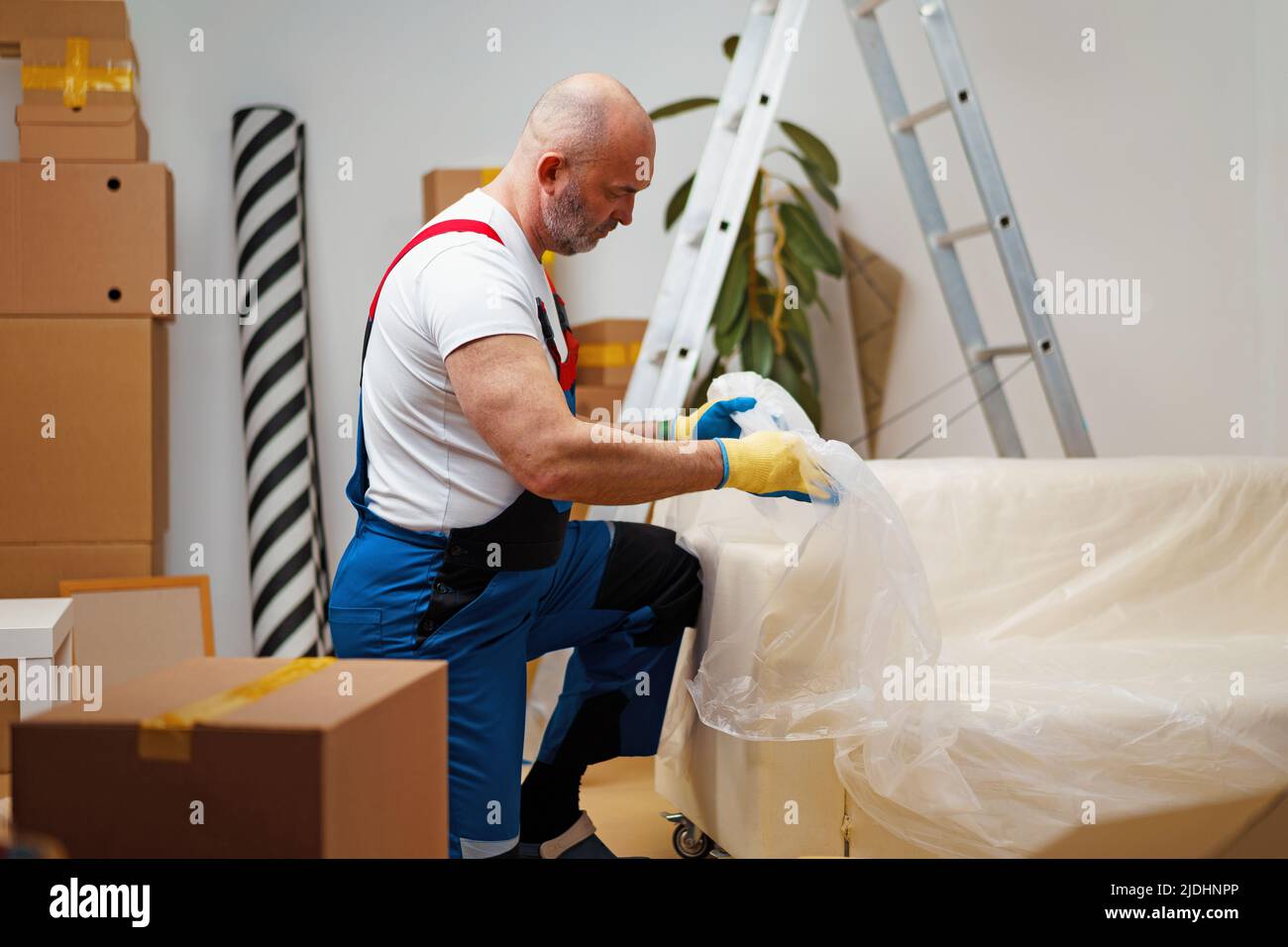 Man mover in uniiform packing sofa for relocation Stock Photo - Alamy