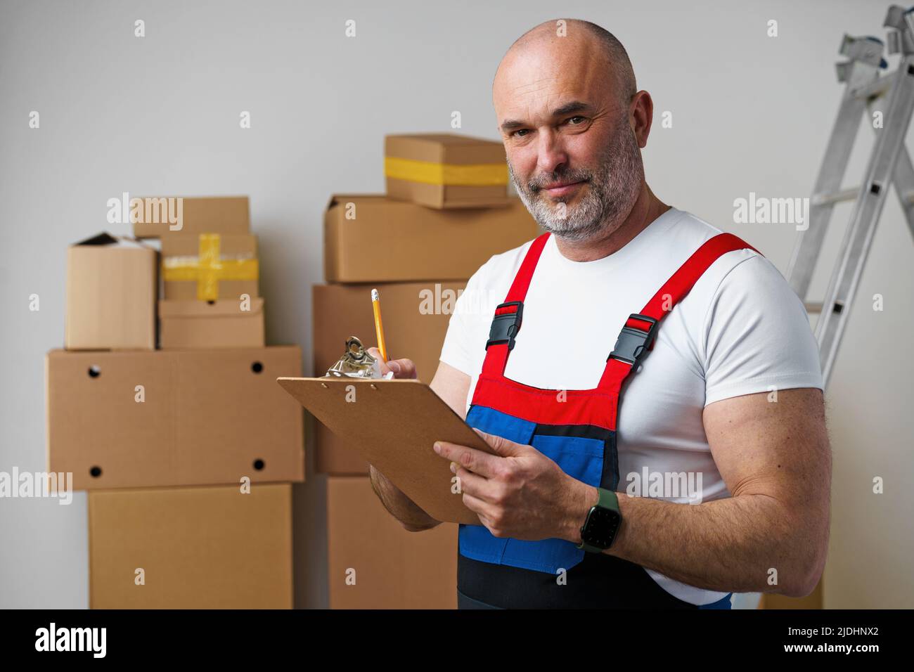 Middle-aged man mover in uniform making notes on clipboard Stock Photo ...