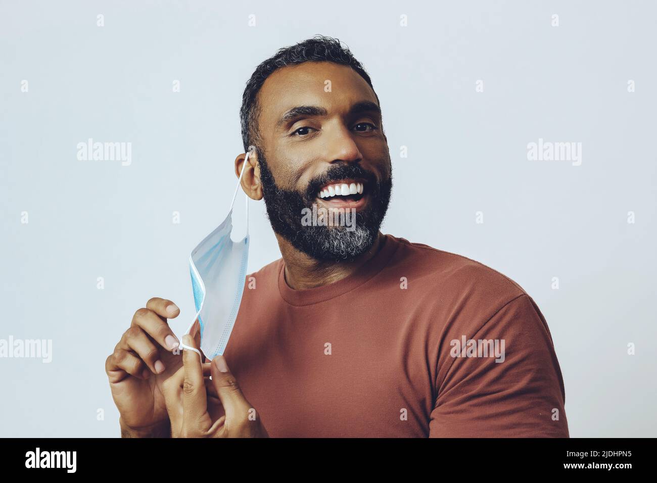headshot mid adult african-american man taking a protective mask off on ...