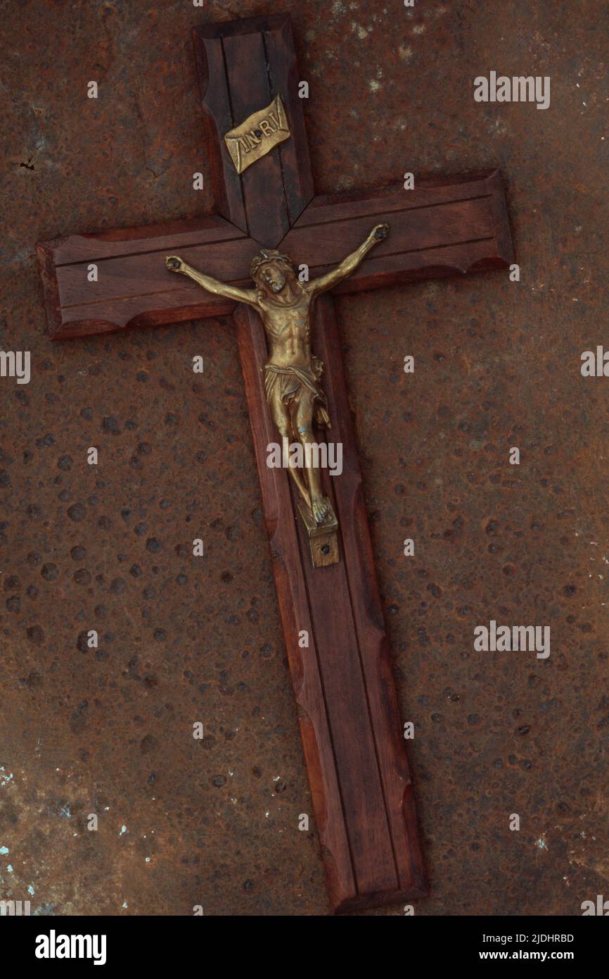 Wooden crucifix with brass figure of Jesus on it lying on rusty metal ...
