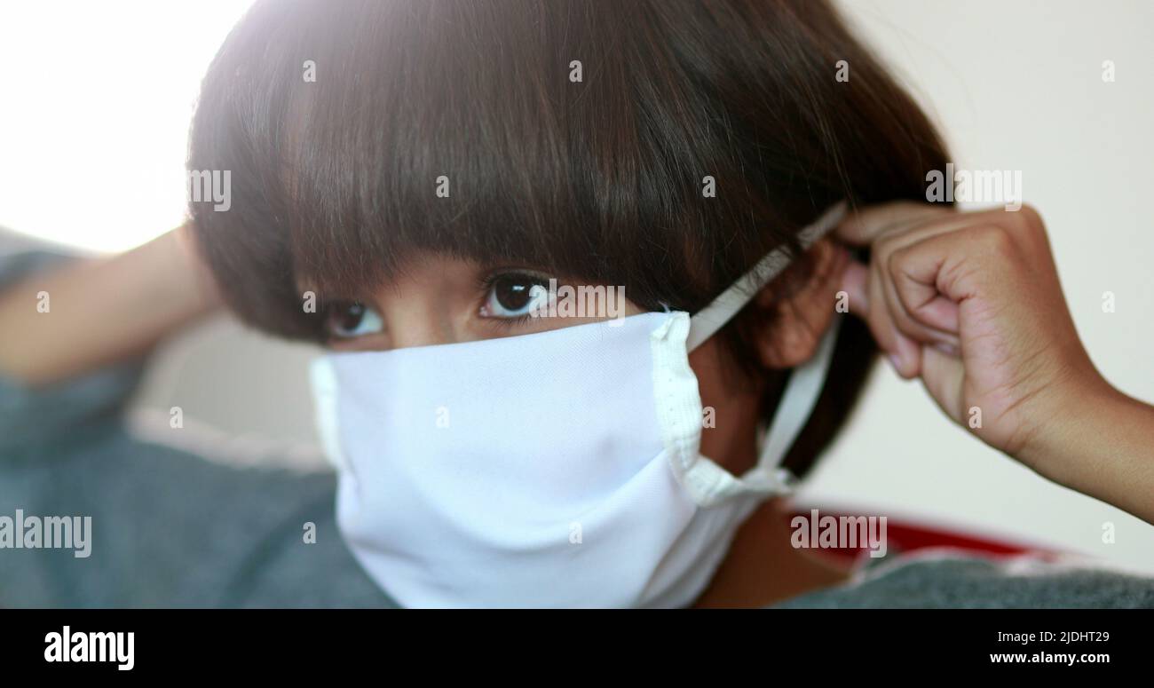 Young boy putting pandemic mask prevention on face, kid wearing ...