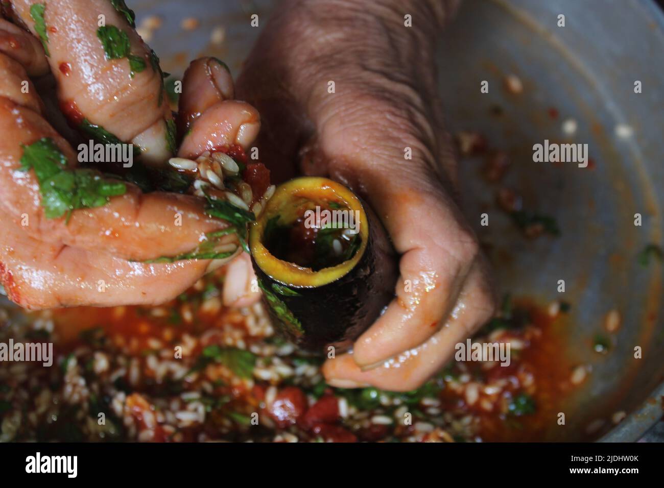 Woman hands preparing eggplants stuffed with rice ingredient. Greek or ...