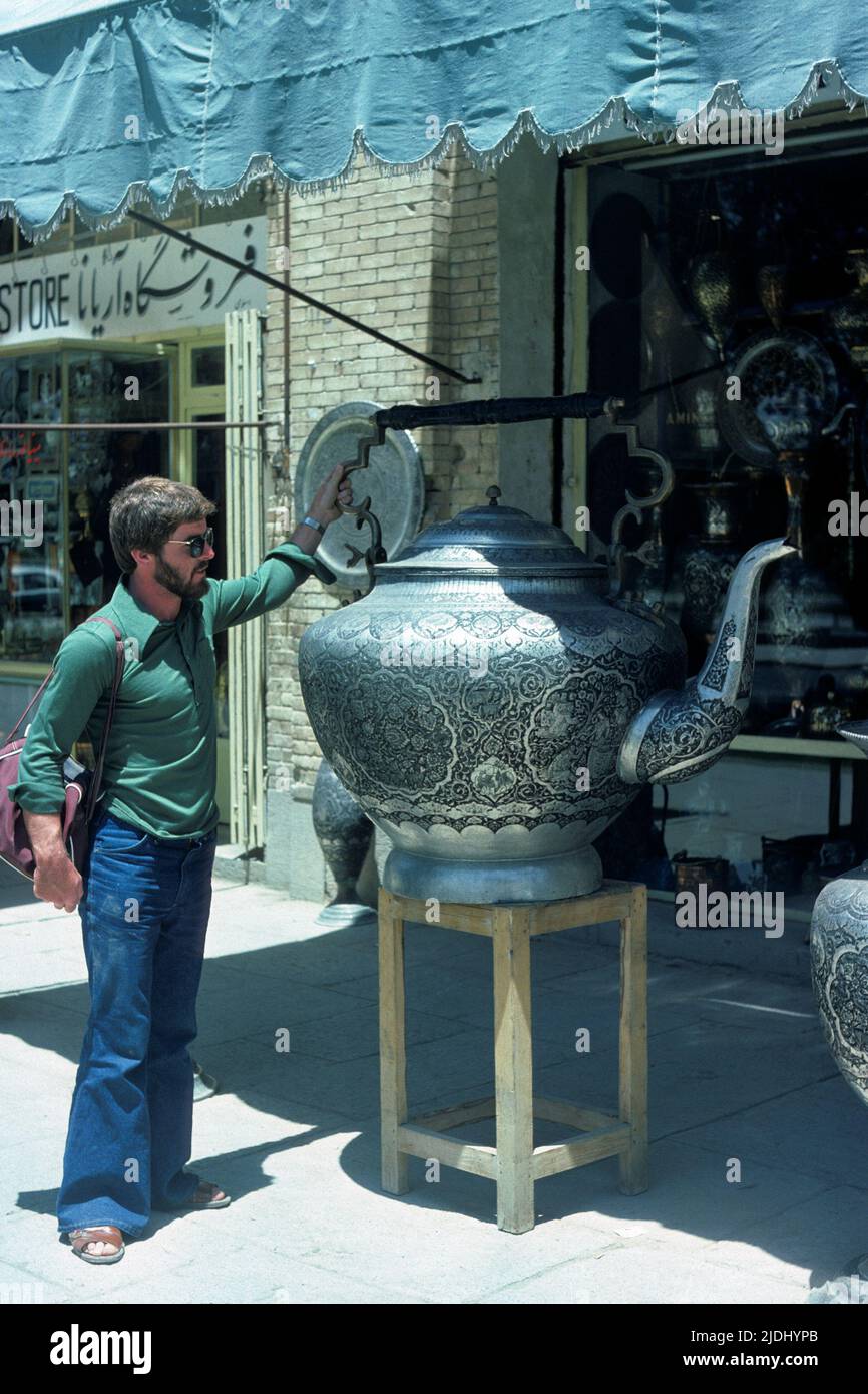 Isfahan Iran 1976 - a tourist inspects a giant metal teapot outside a ...