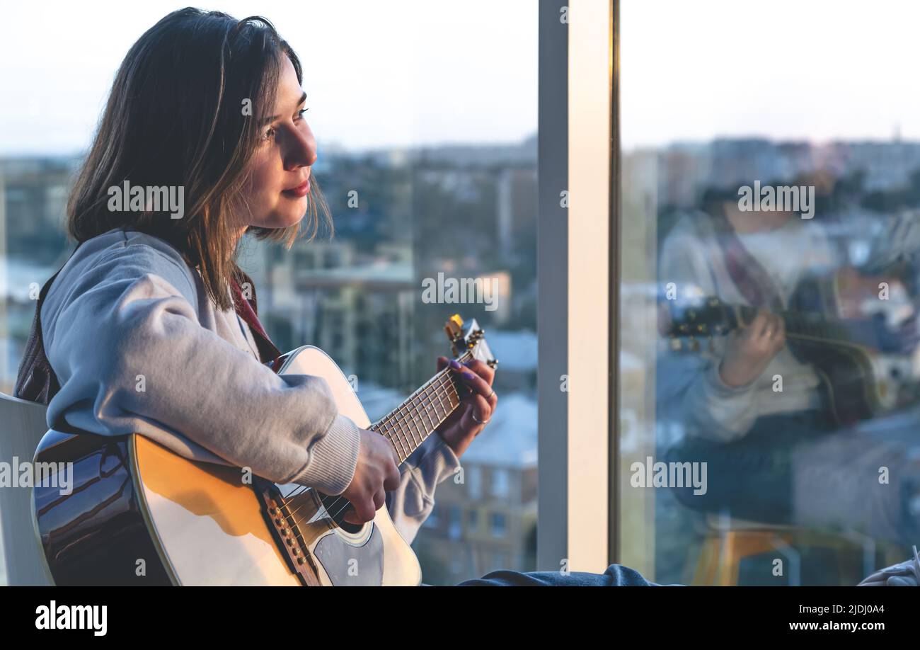 A young woman plays an acoustic guitar by the window Stock Photo - Alamy