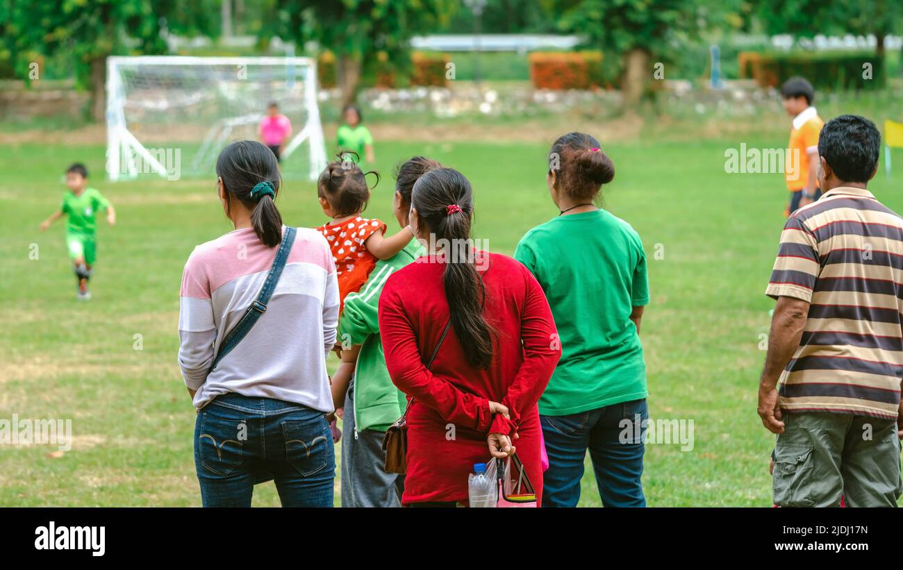 Back view of Moms watch and cheering their sons playing football in ...