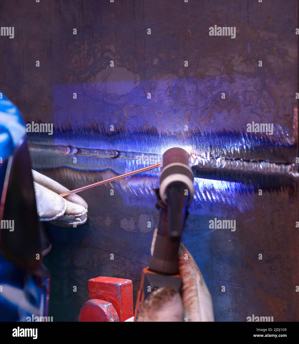 welder hands weld two pieces of metal using argon torch and filler rod ...