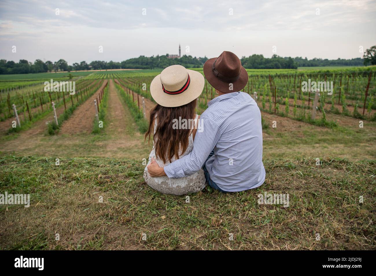 A couple sitting on the ground hug each other as they look at the ...