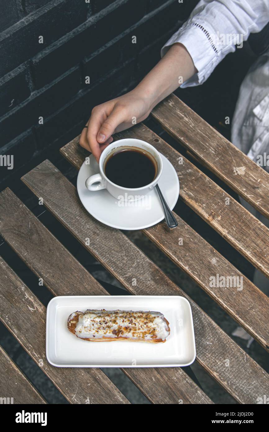 Cup of coffee and eclair on a wooden table close-up Stock Photo - Alamy