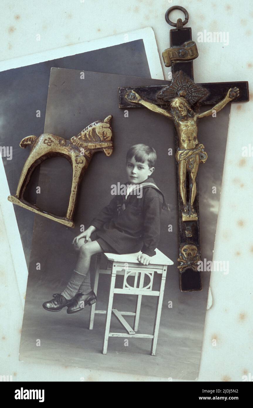Ebony and brass crucifix lying on antique paper with sepia photo of boy ...
