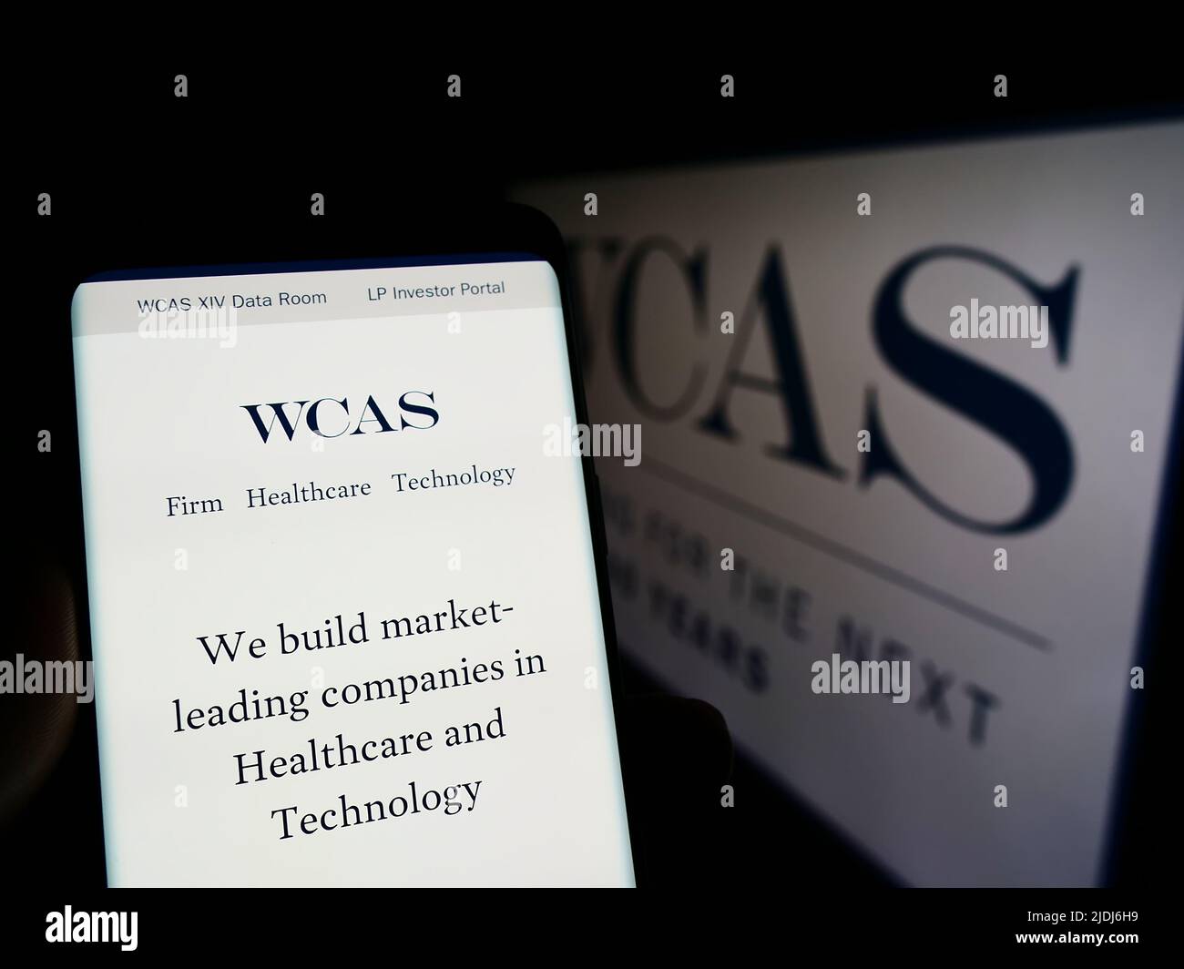 Person holding smartphone with website of company Welsh, Carson ...