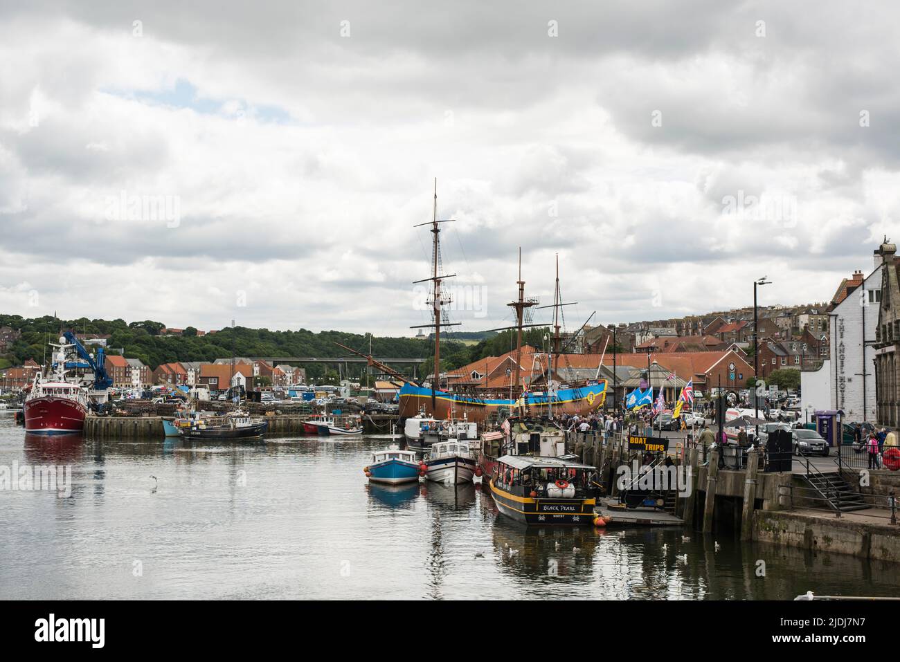 Whitby docks with large trawler and many small boats, urban part of ...