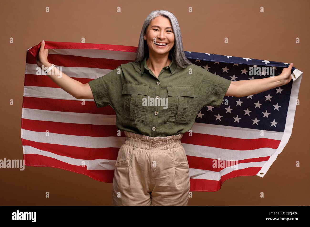 Happy senior woman wearing casual style clothes, holding flag of united ...