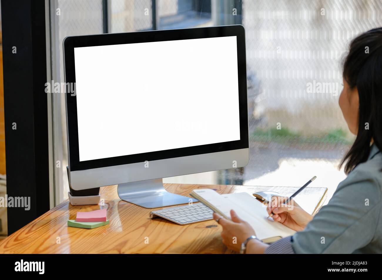 A white screen computer placed on the desk at work. Can put text or ...