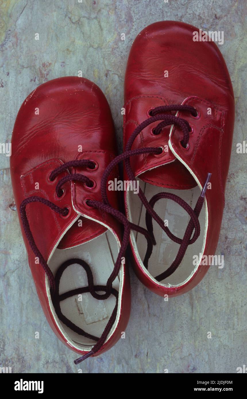 Pair of young childs lace-up red shoes shiny but slightly scuffed lying ...