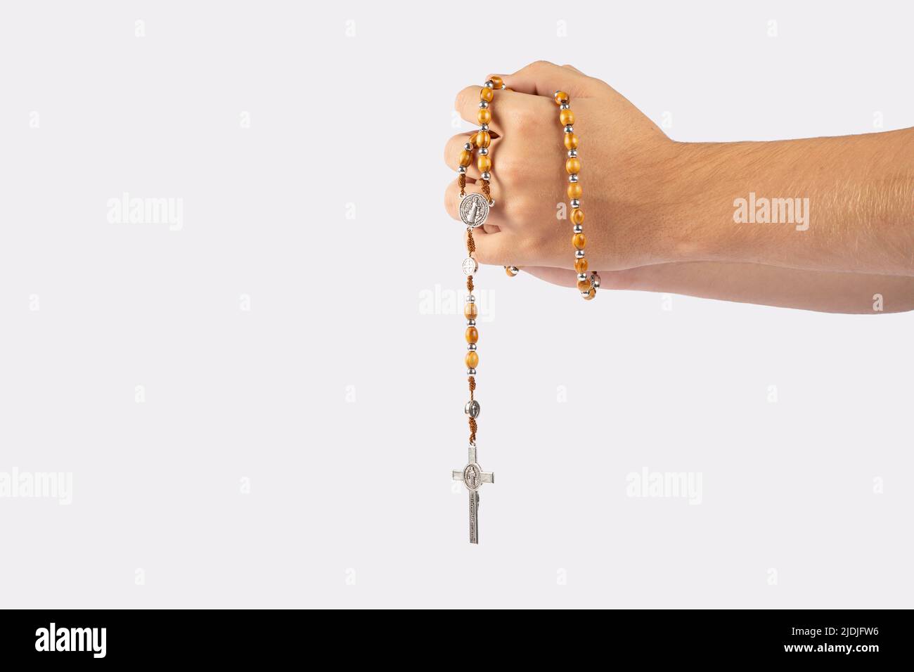 Folded hands of a young man holding a rosary during a pray isolated on ...