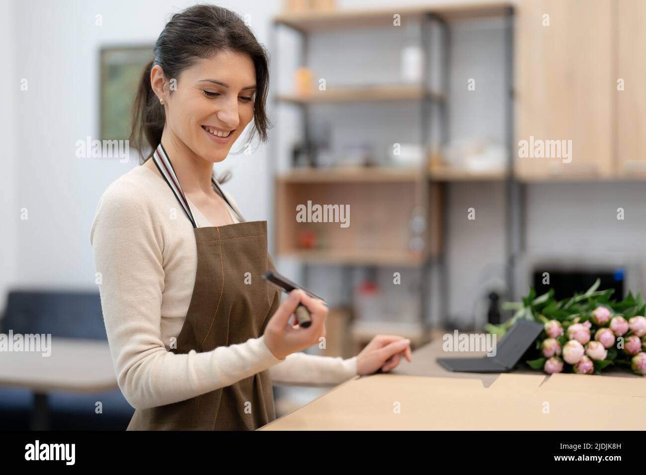 Woman hands placing a stamp on a present box while working in the shop. Prepare order for ...